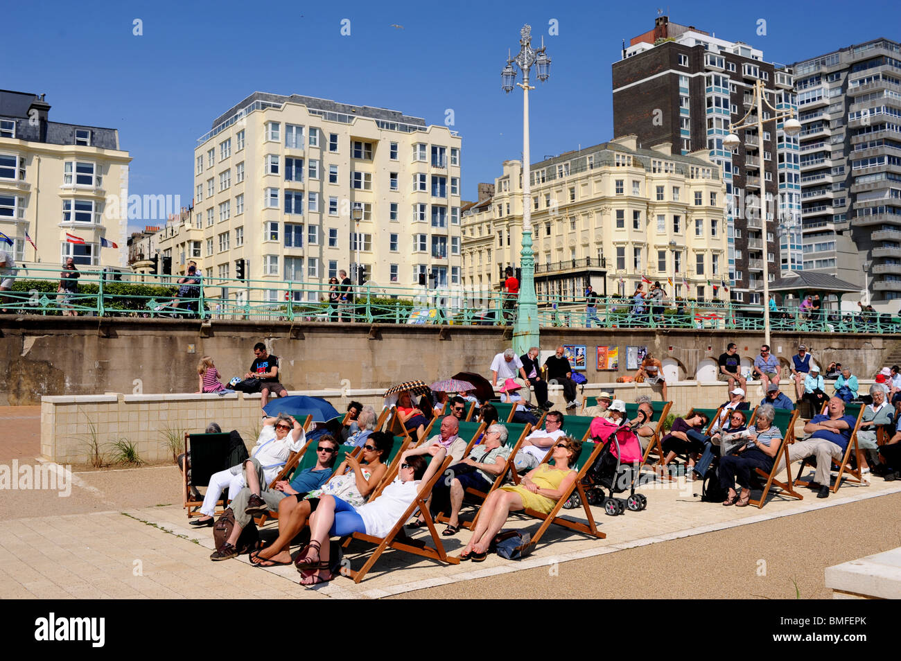 Crowd sunbathing in deckchairs as they listen to a band playing at the ...