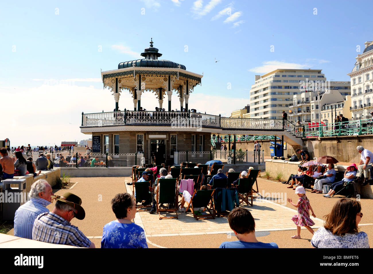 Crowd sunbathing in deckchairs as they listen to a band playing at the ...