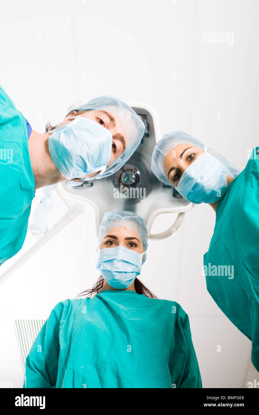 Team of medical professionals looking down at patient in surgical ...