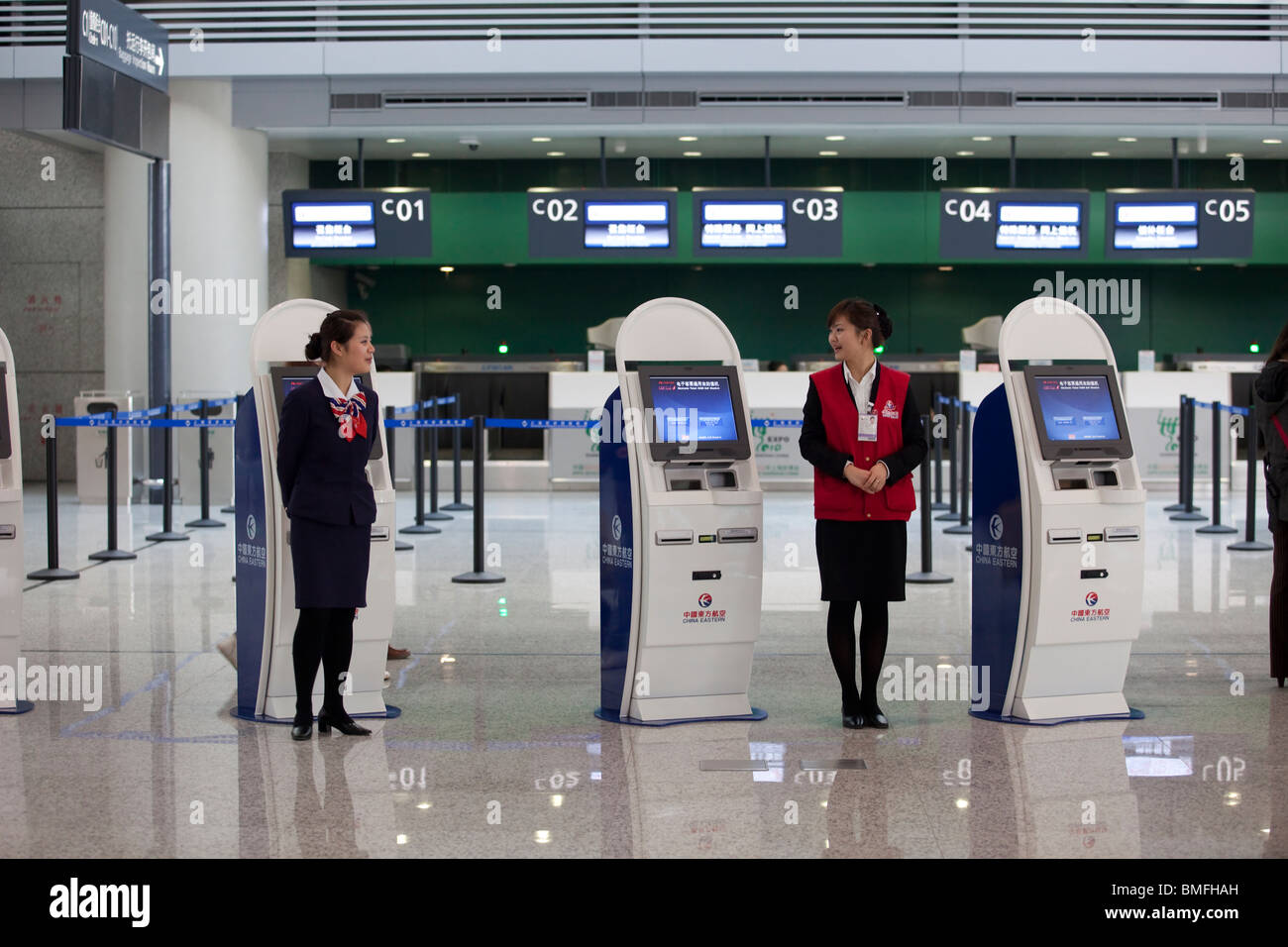 Stewardesses at the self check-in machine to help travelers, in ...