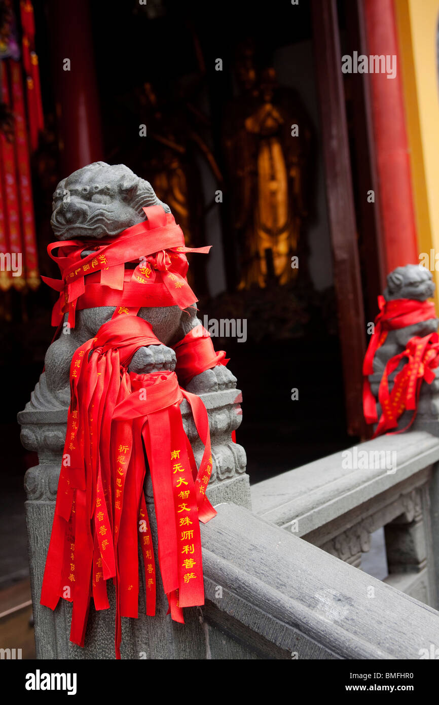 Stone lion covered with red prayer ribbon, Jade Buddha Temple, Shanghai ...