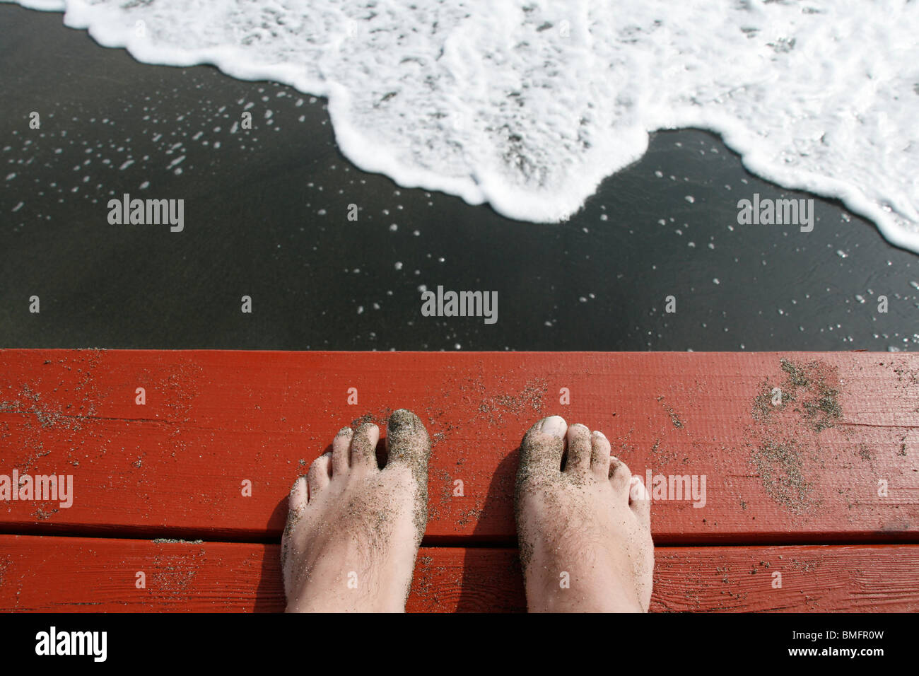 man standing on red jetty by waves in sea Stock Photo - Alamy