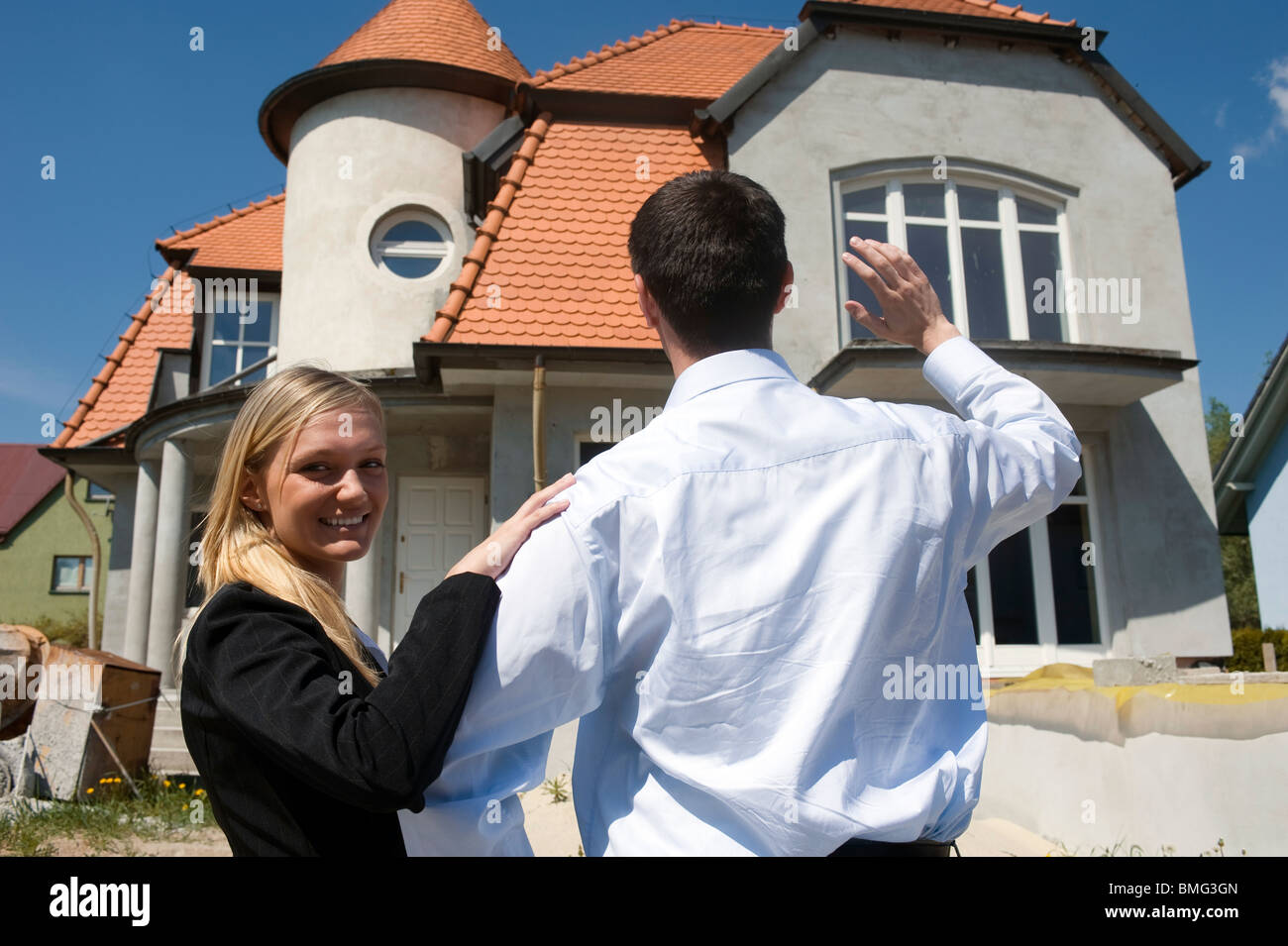 Man pointing towards a house with a woman standing beside her Stock ...