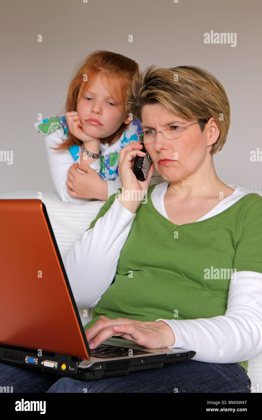 a mother trying to work on her computer while her daughter is watching ...