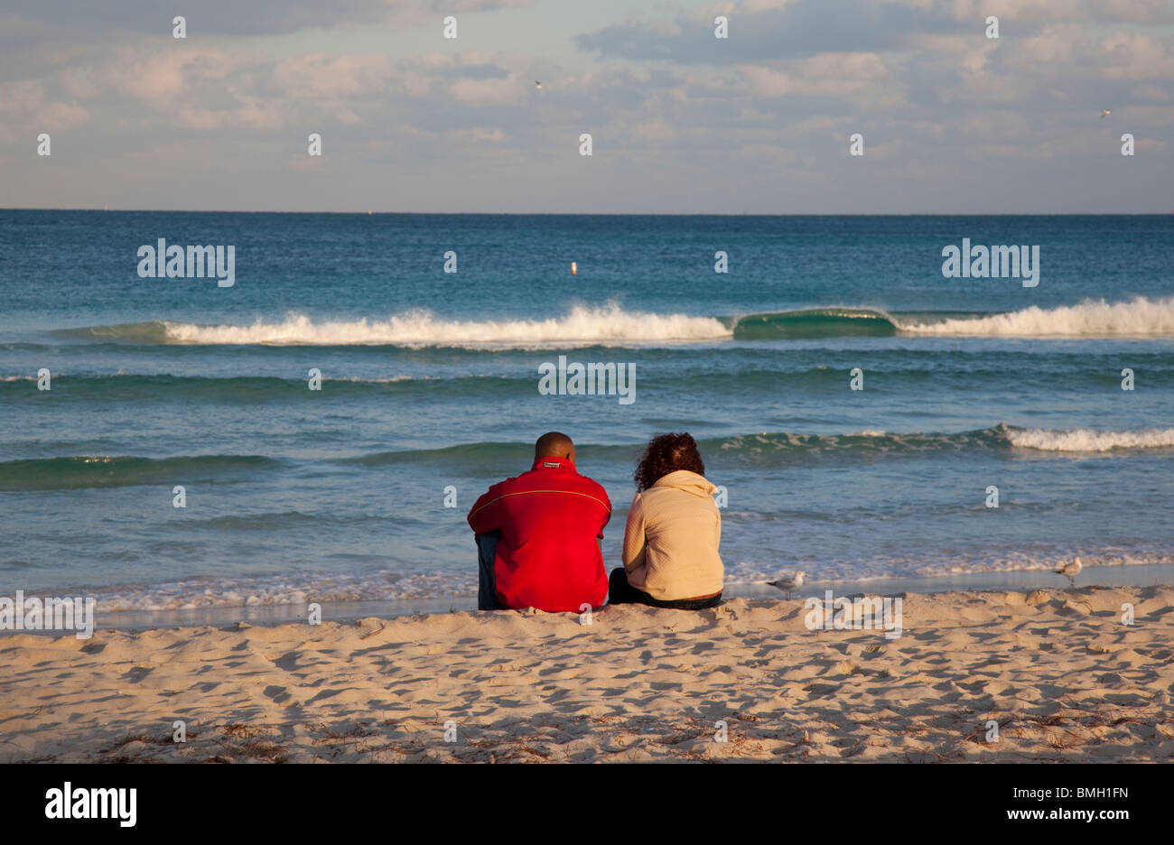 Couple sat on Miami Beach looking at the sea early morning Stock Photo ...