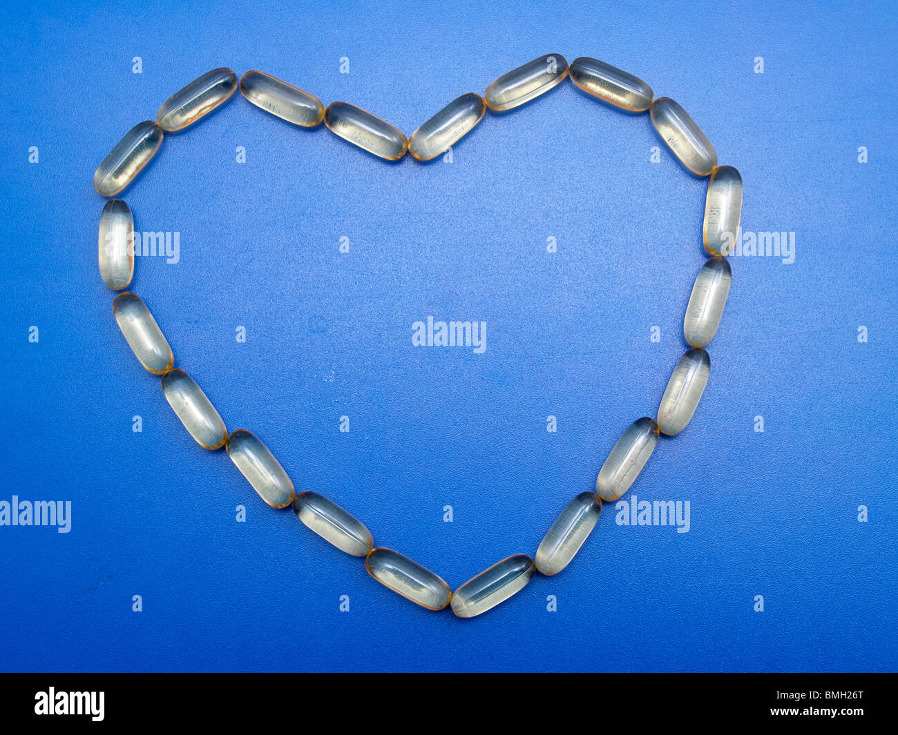 Omega 3 capsules heart shape on blue background Stock Photo - Alamy