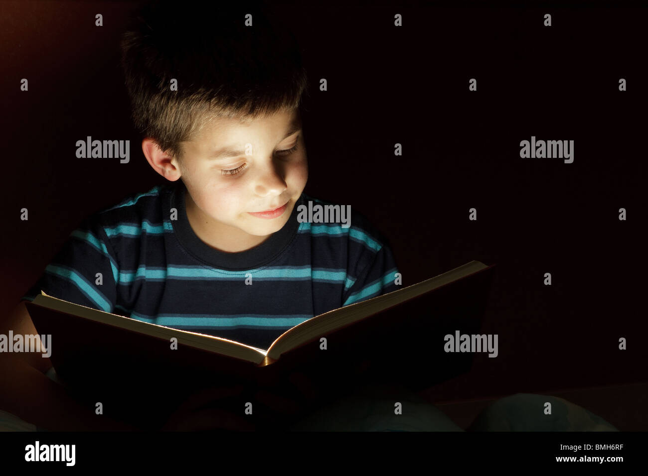 Boy reading bedtime story, dark photo, key light coming from book Stock ...