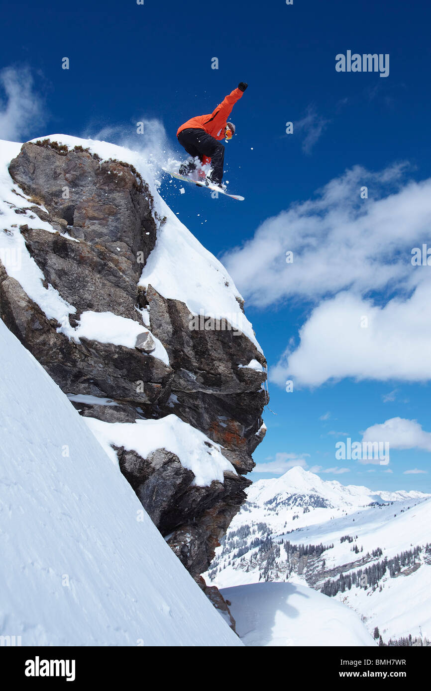 Male snowboarder jumping from cliff Stock Photo - Alamy