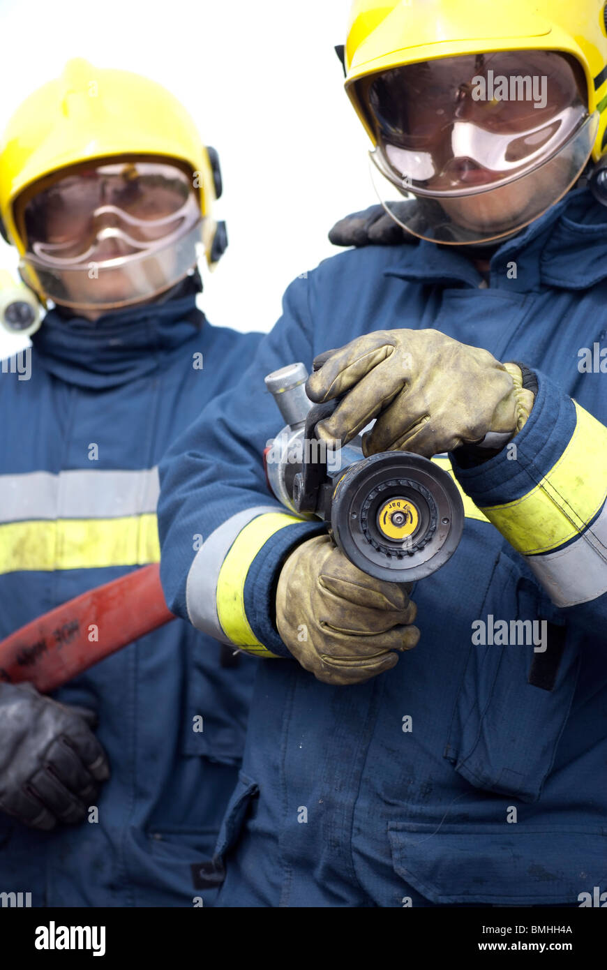 Two firefighters holding hand held water hose Stock Photo - Alamy