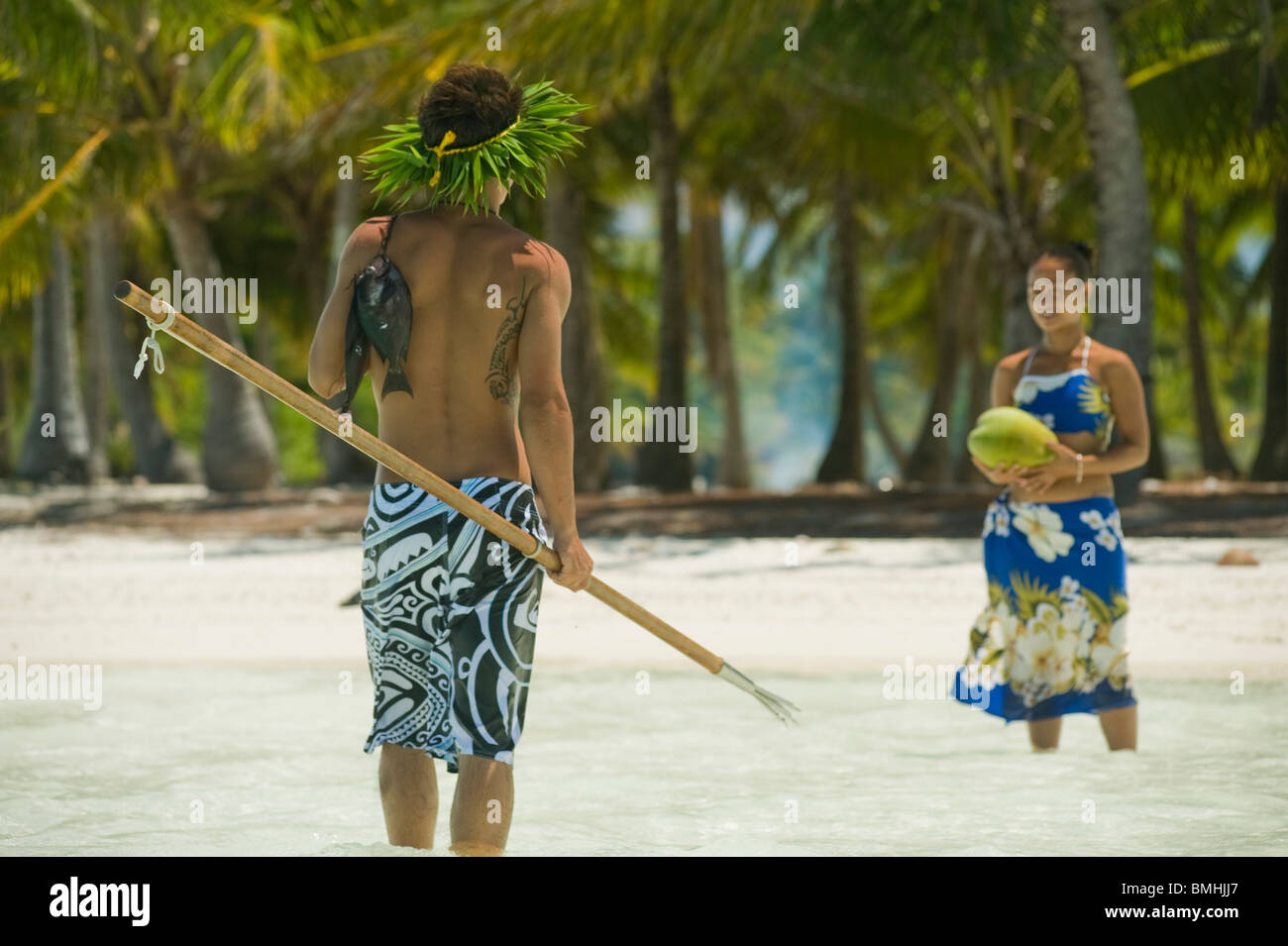 A tahitian fisherman has caught many fishes with a trident harpoon and ...