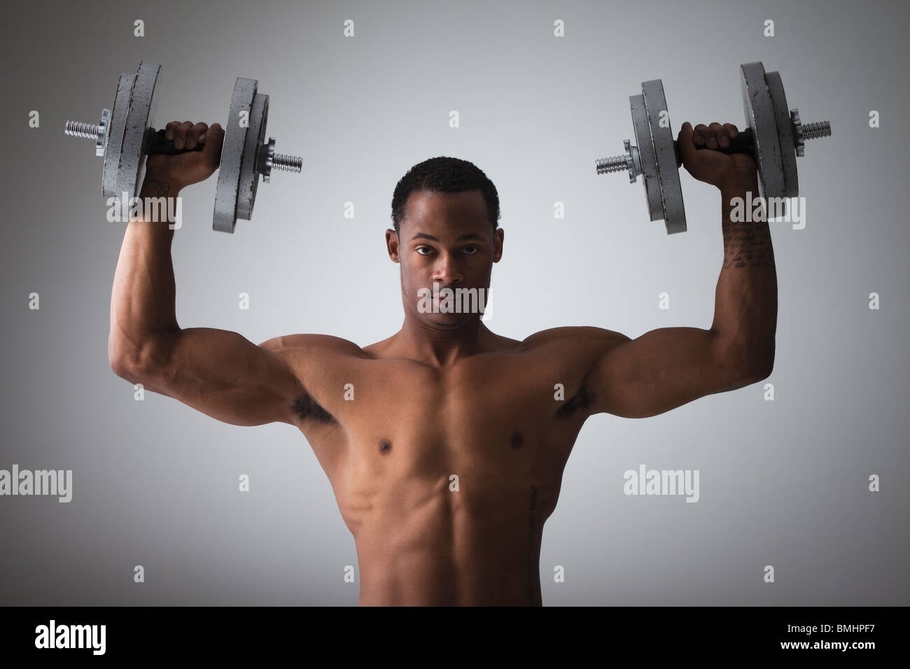 Muscular man lifting dumbbells Stock Photo - Alamy