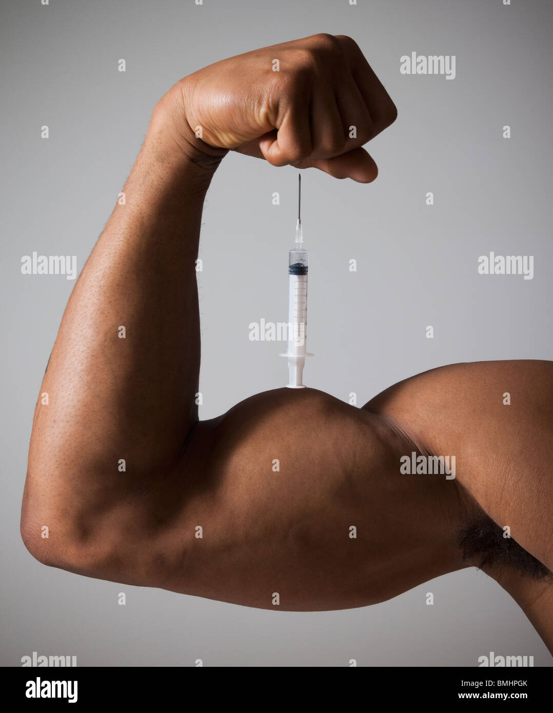 Syringe perched on a flexed muscular arm Stock Photo - Alamy