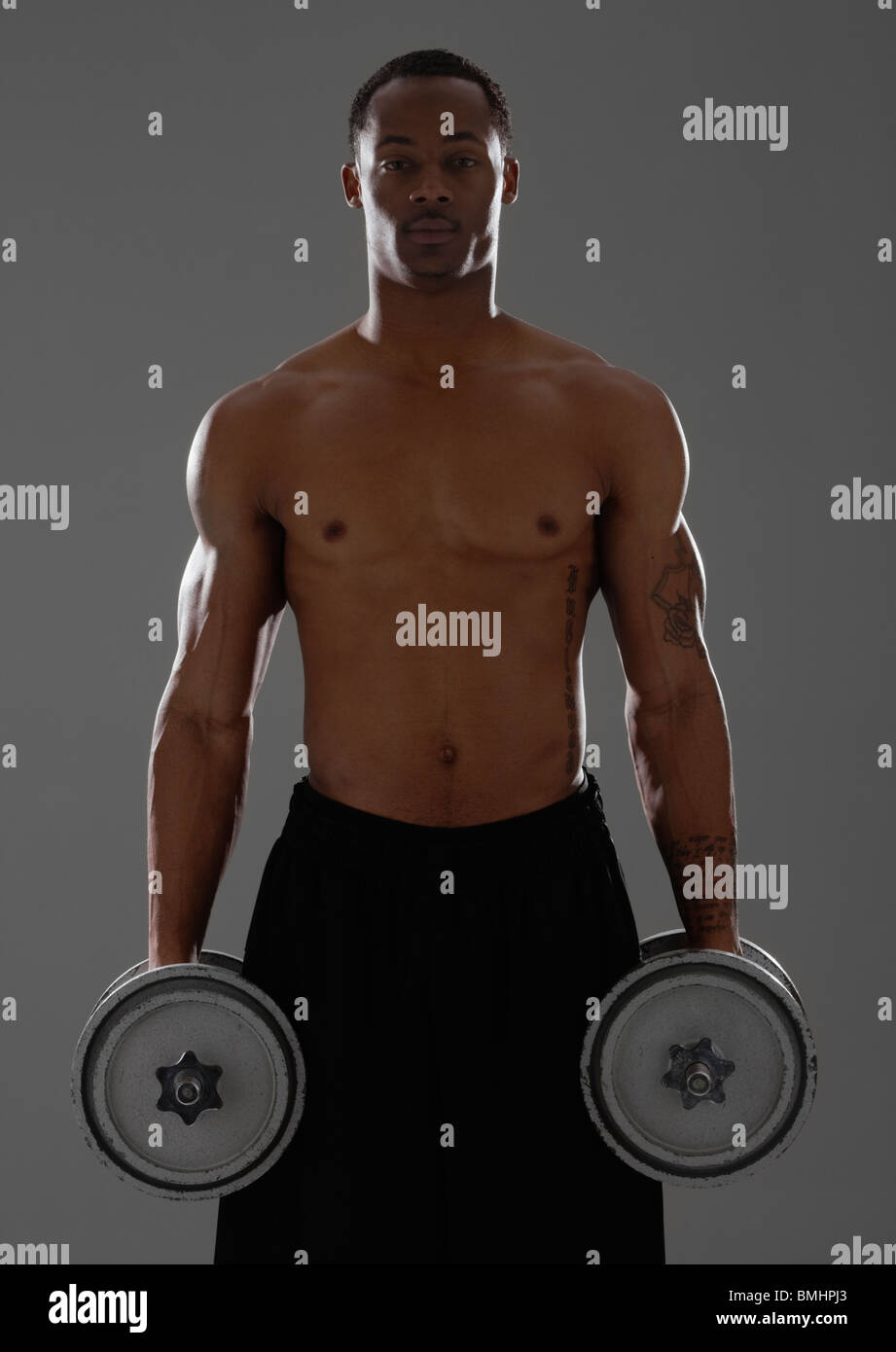 Physically fit man lifting dumbbells Stock Photo - Alamy