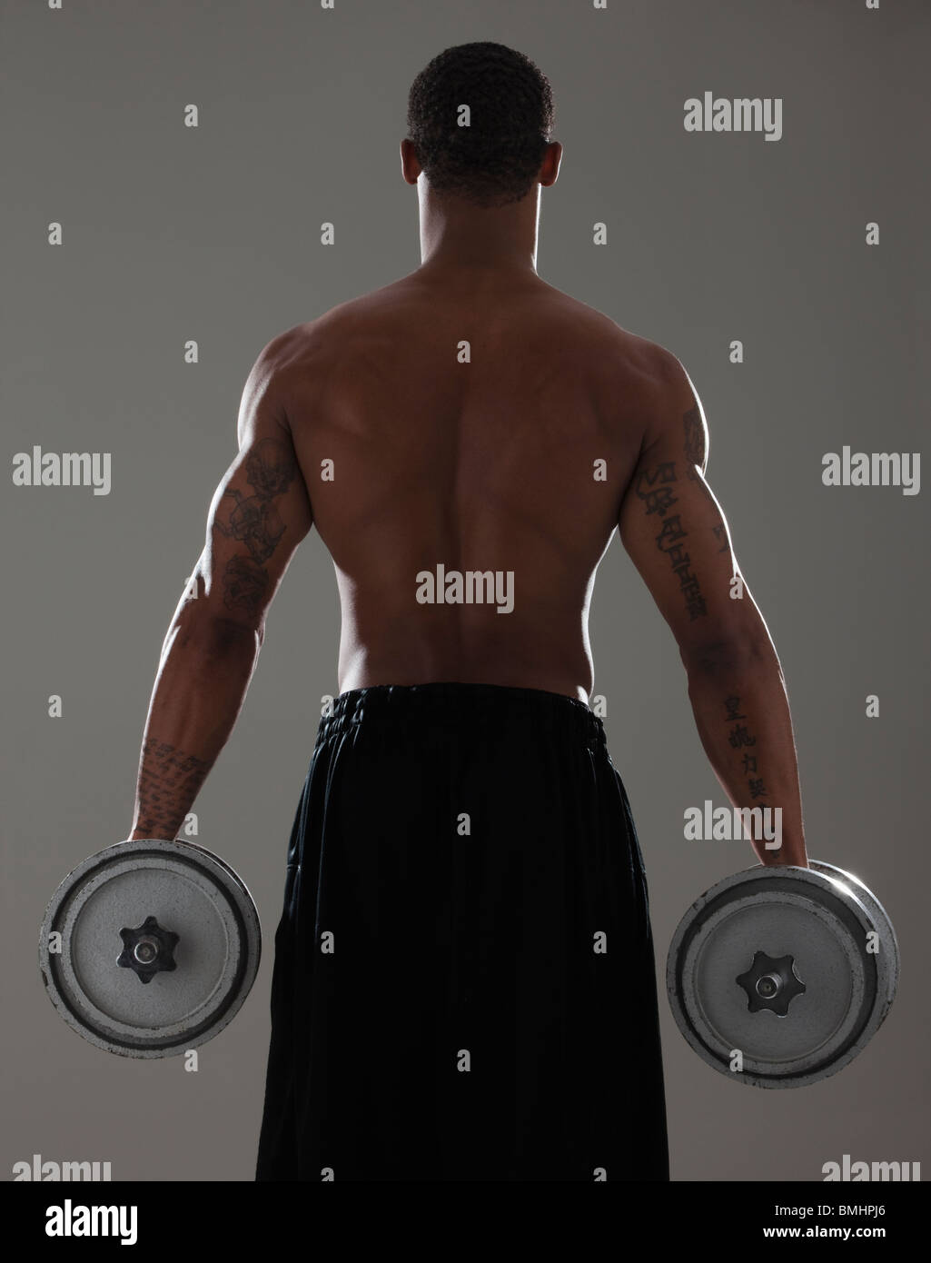 Physically fit man lifting dumbbells Stock Photo - Alamy