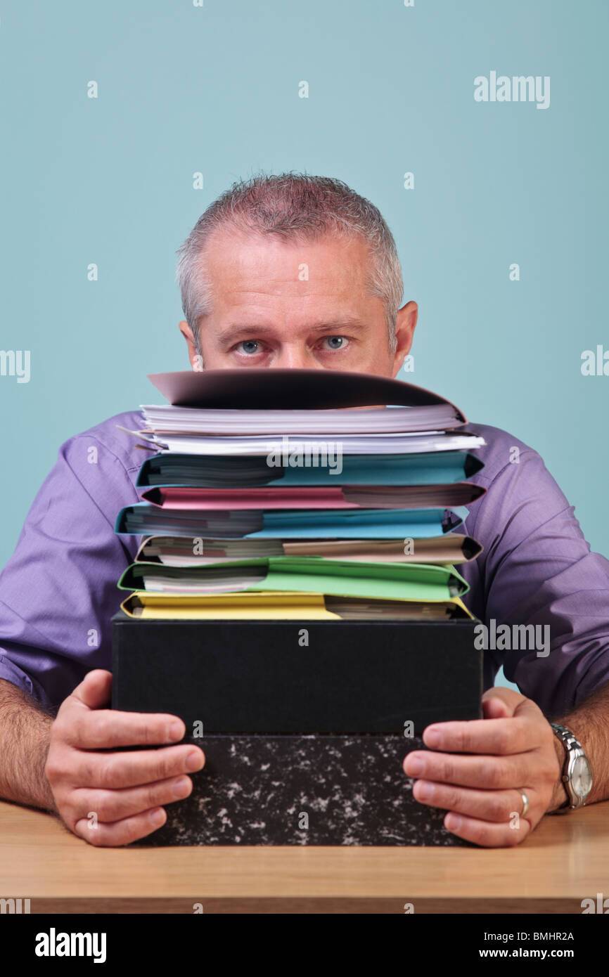 Man sitting behind a stack of paper work Stock Photo - Alamy