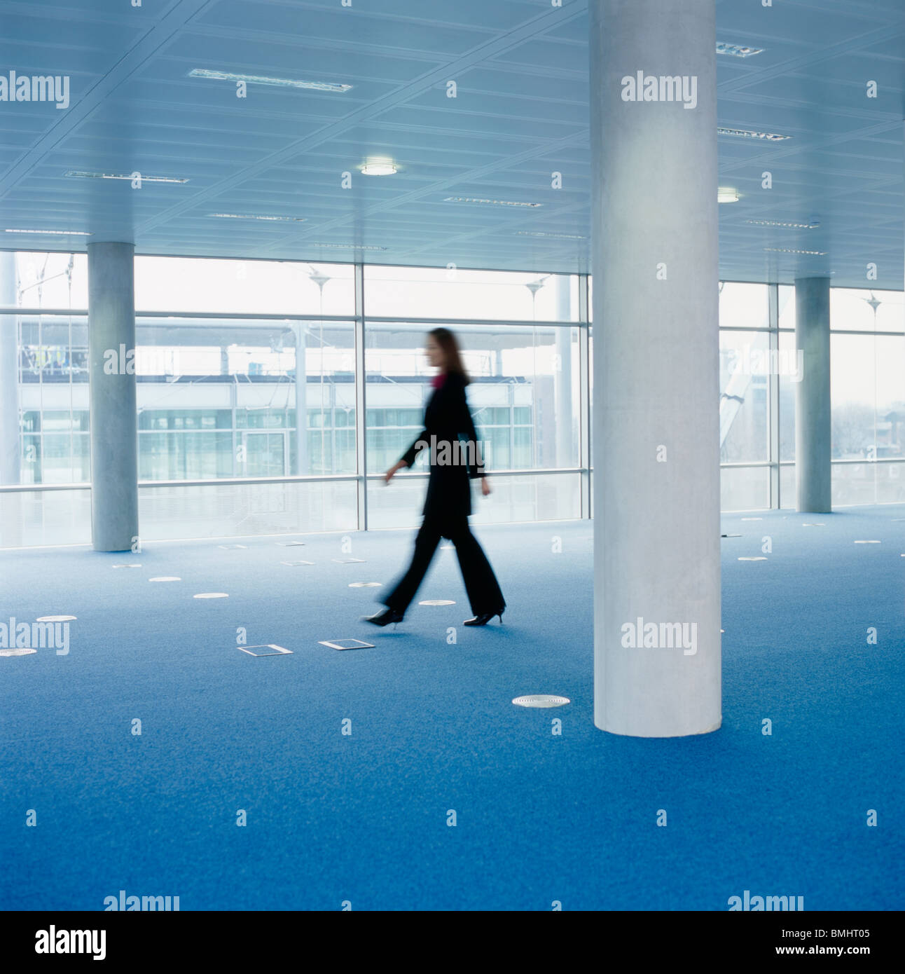 Business woman walking through new office building Stock Photo - Alamy