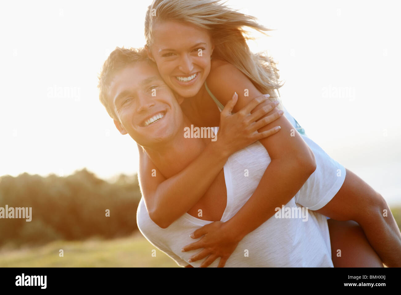 Man giving girlfriend a piggy back ride Stock Photo - Alamy