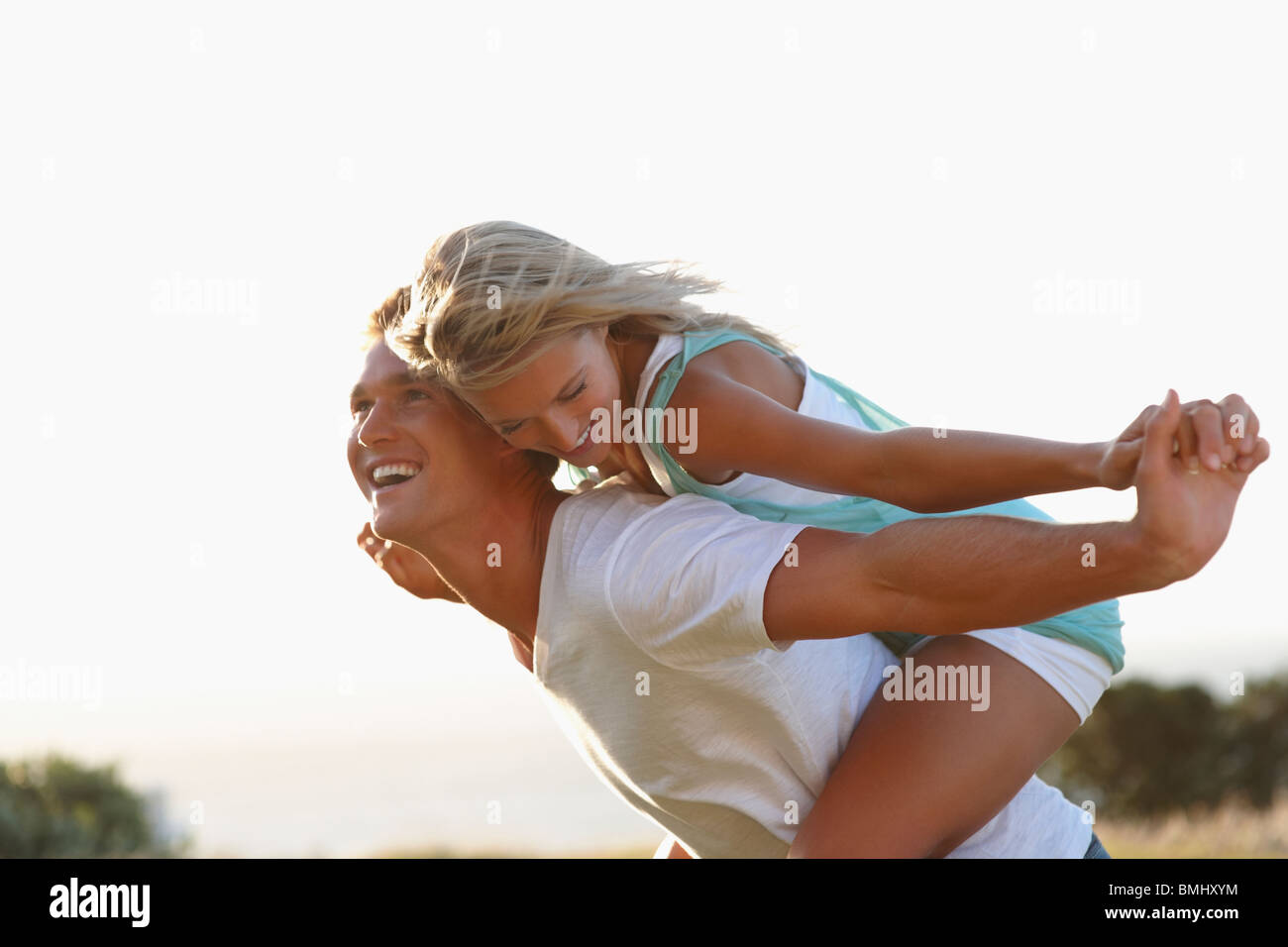 Man giving girlfriend a piggy back ride Stock Photo - Alamy