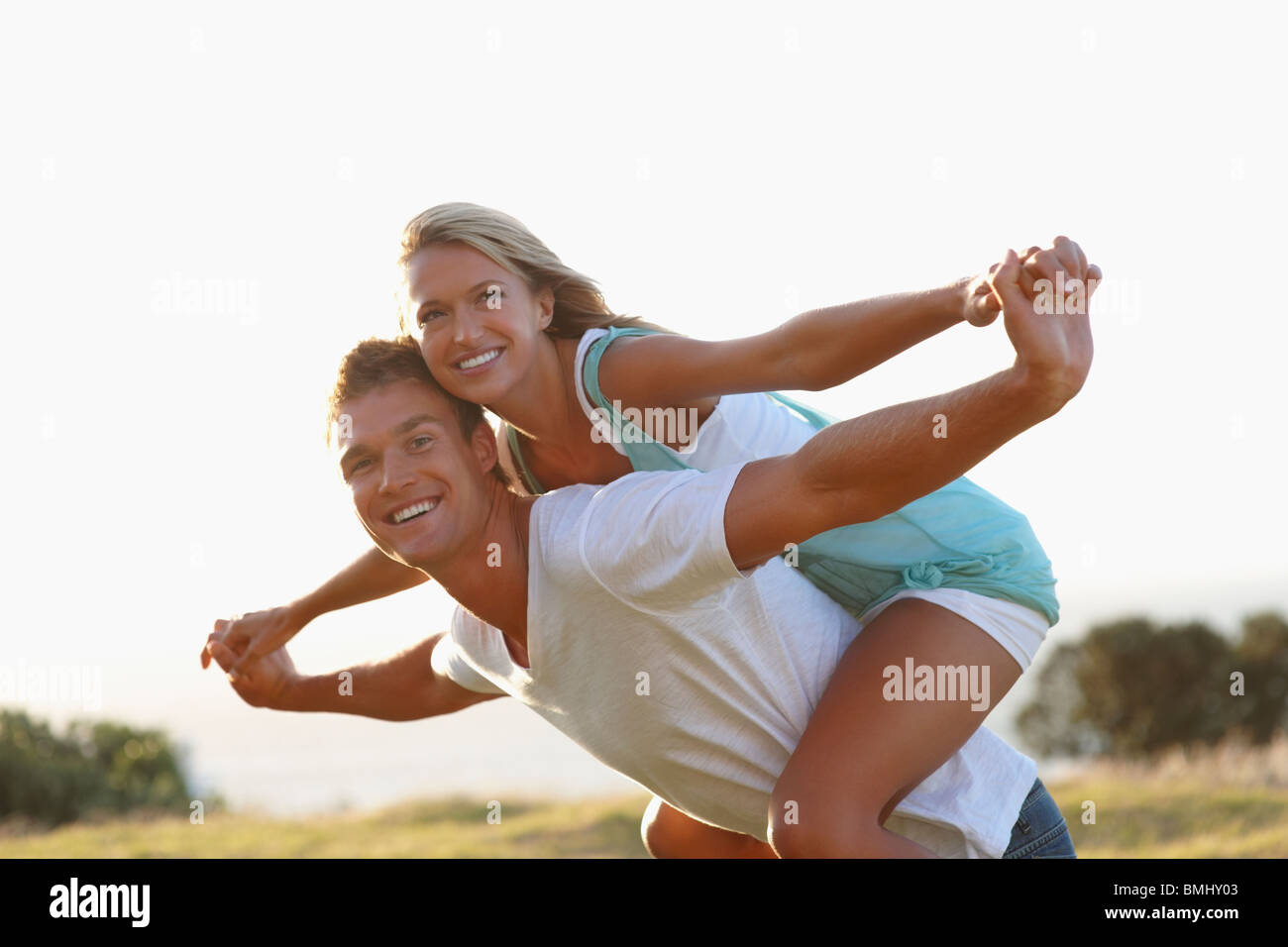 Man giving girlfriend a piggy back ride Stock Photo - Alamy