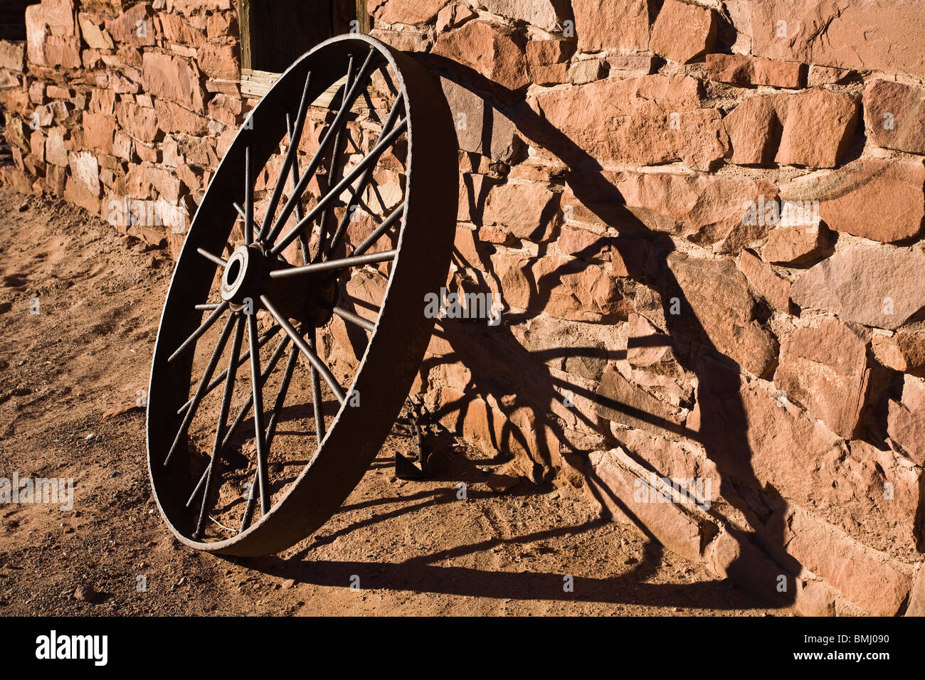 Large metal wheel up against stone building wall Stock Photo - Alamy
