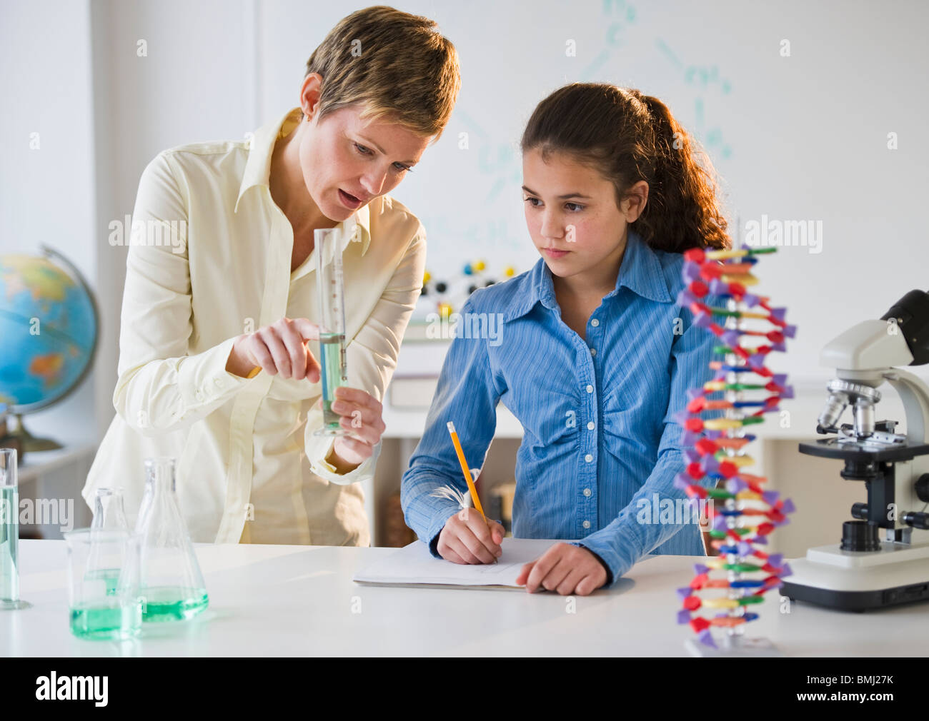 Teacher helping student in science lab Stock Photo - Alamy
