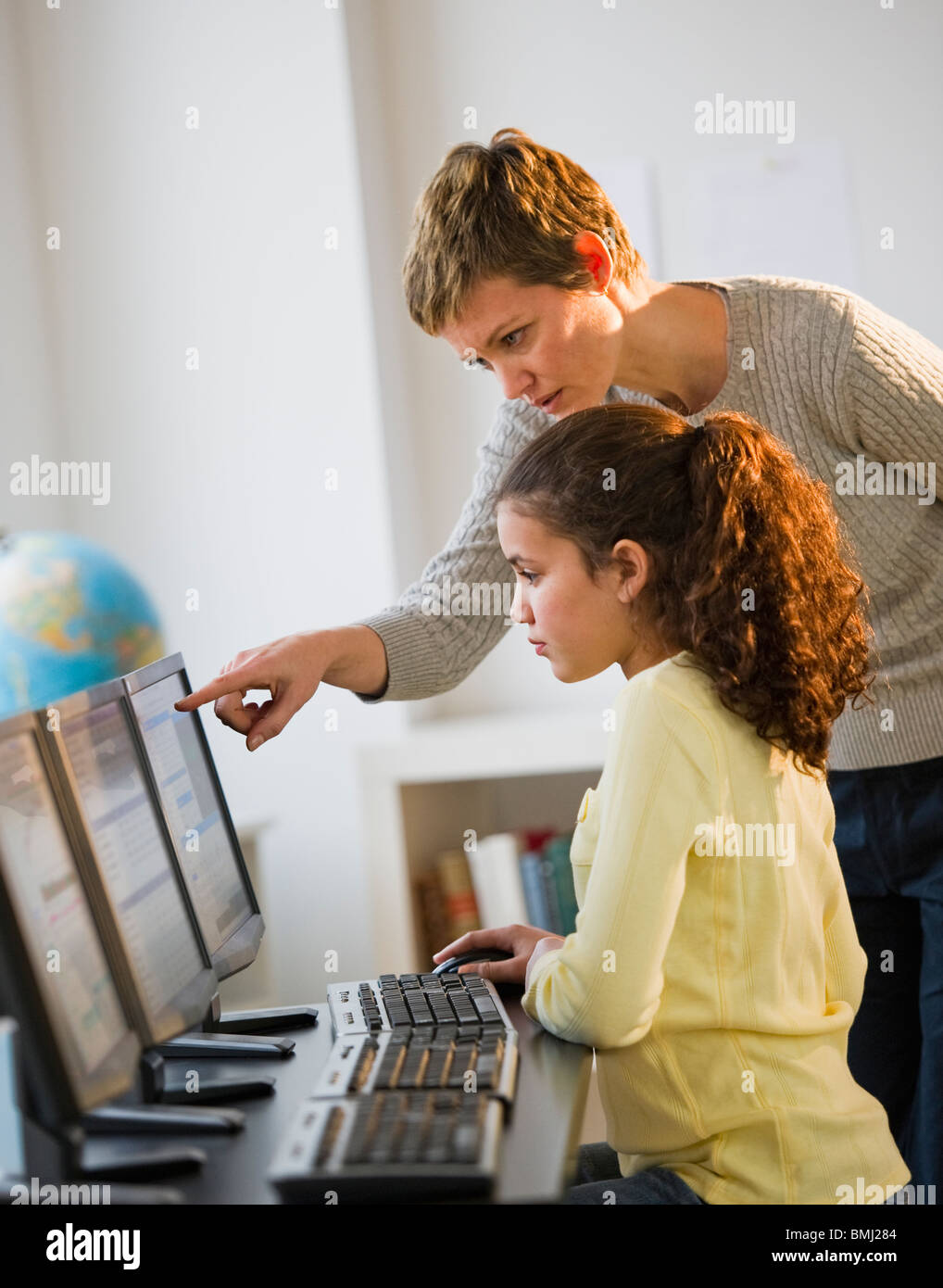 Teacher helping student in computer lab Stock Photo - Alamy