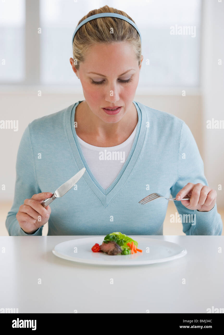 Woman eating small portion of food Stock Photo - Alamy