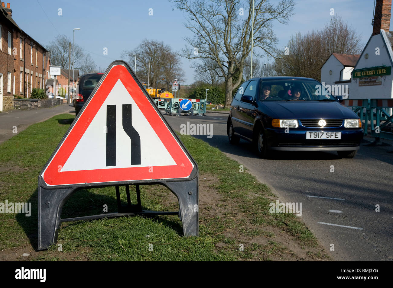 Car passing a road sign and barriers on an English road during repair ...