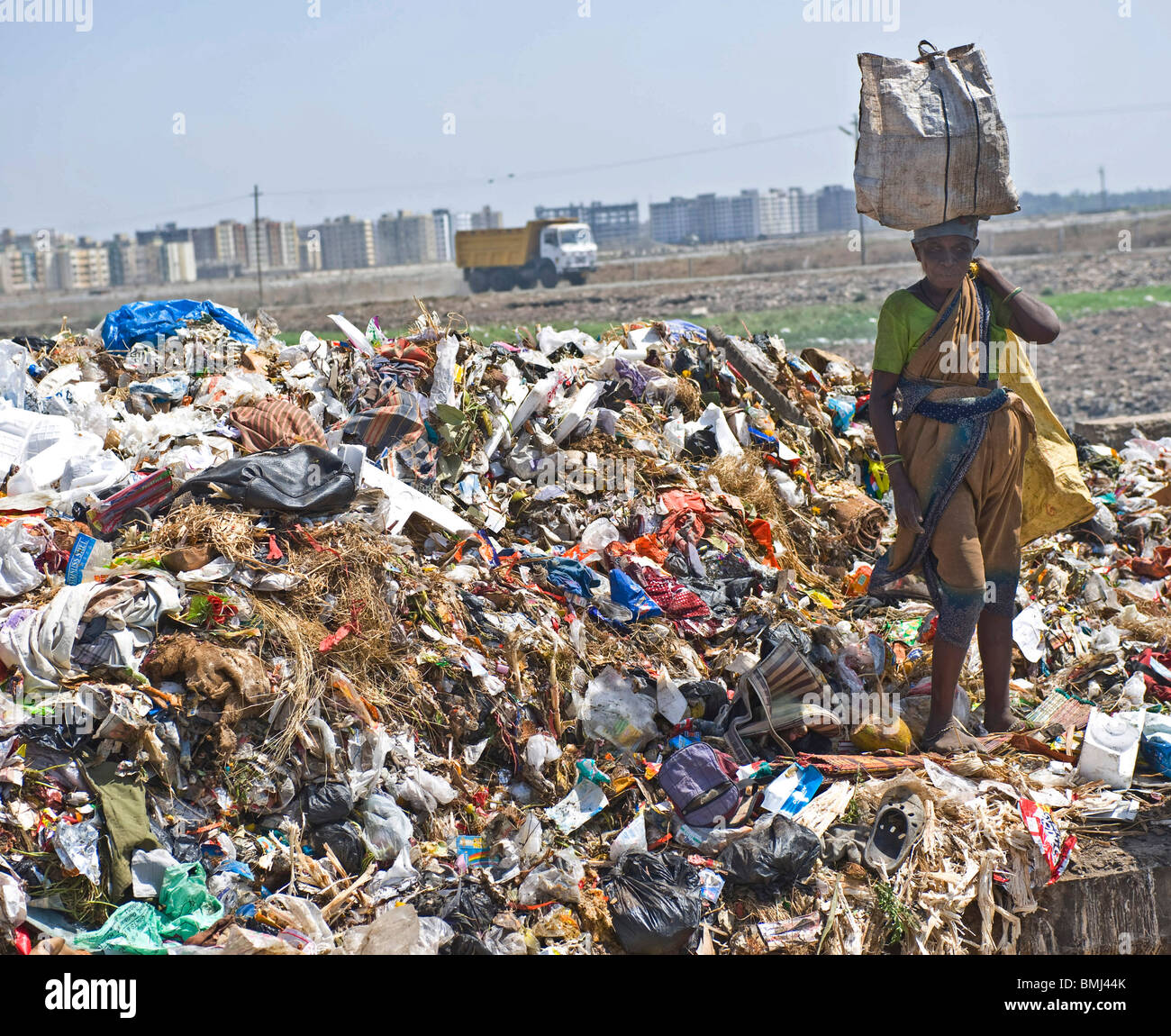A older woman rubbish recycling collector or ragpicker gathers rubbish ...