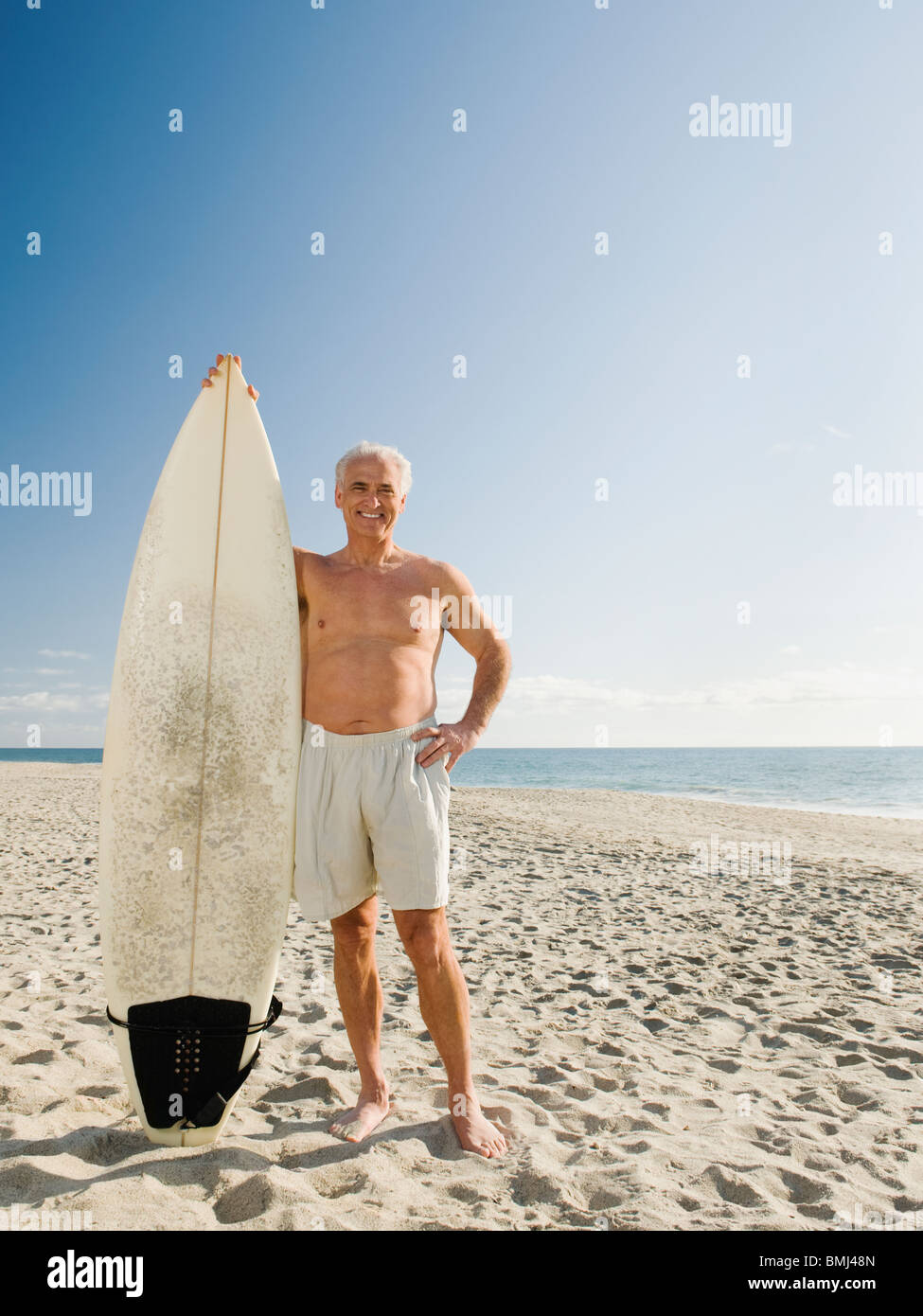 Man holding surfboard on beach Stock Photo - Alamy