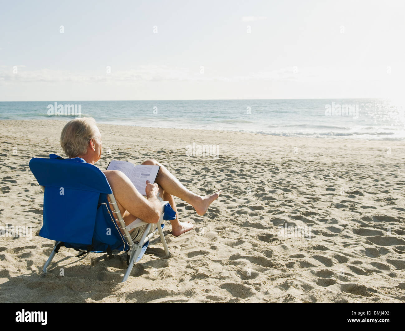 Man relaxing in beach chair Stock Photo - Alamy