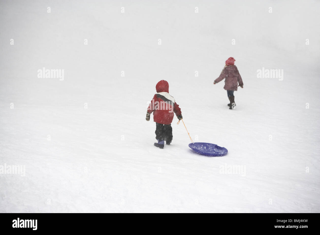 Kids pulling sled up snowy hill Stock Photo - Alamy