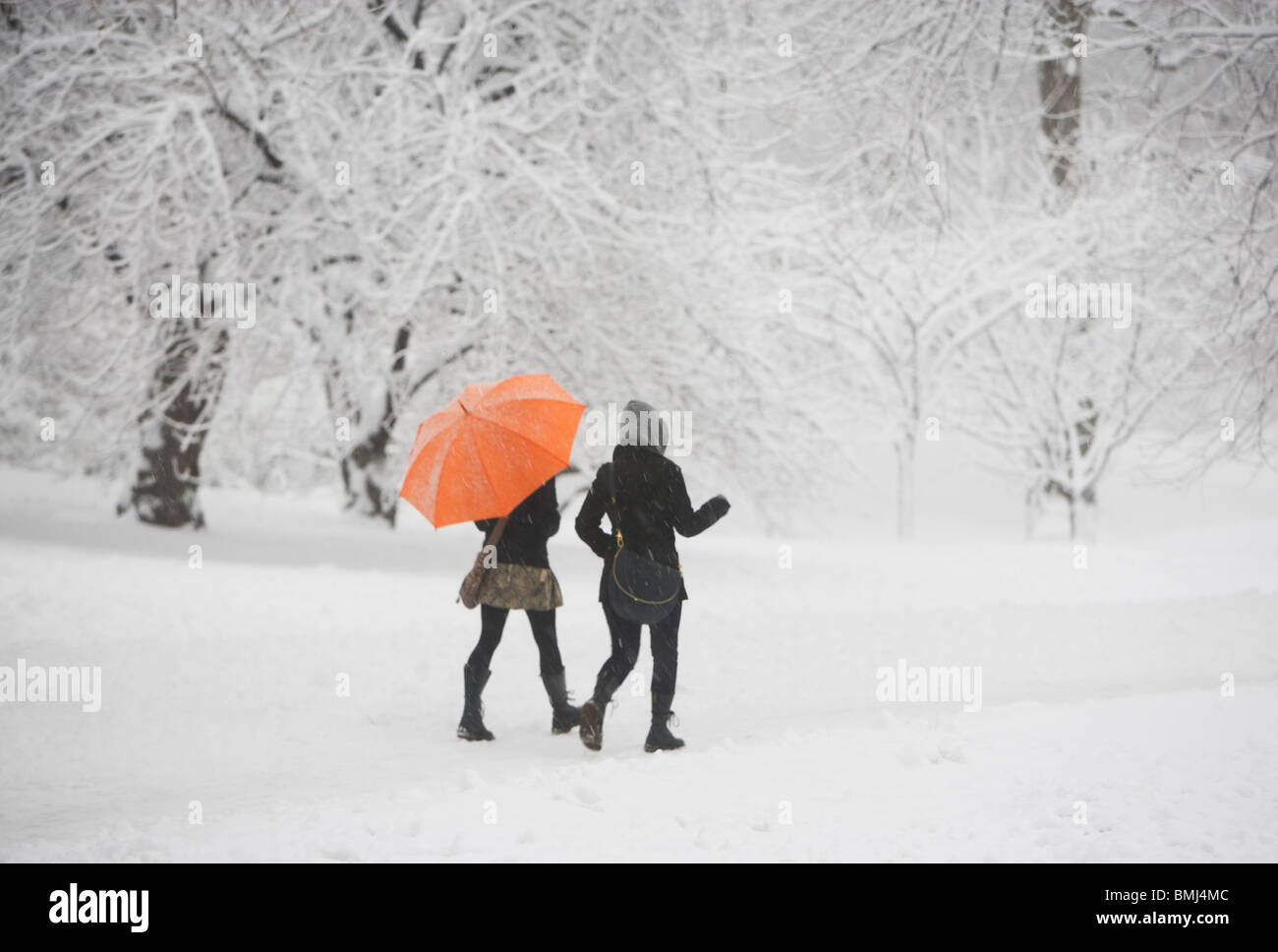 Two girls walking through snowy park Stock Photo - Alamy