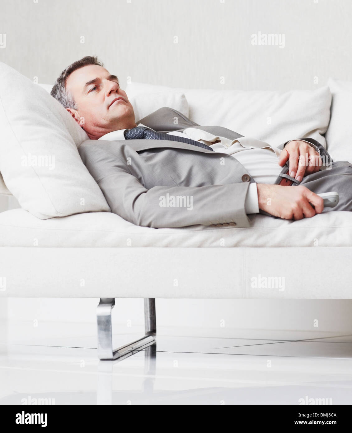 Businessman resting on couch Stock Photo - Alamy