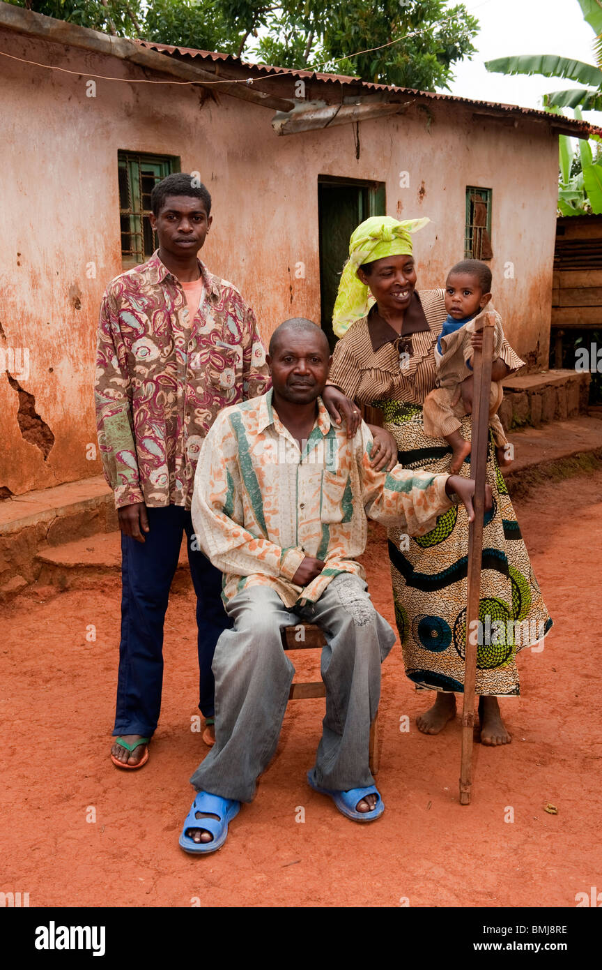 Rwandan family out side home. Father is disabled and uses a crutch ...