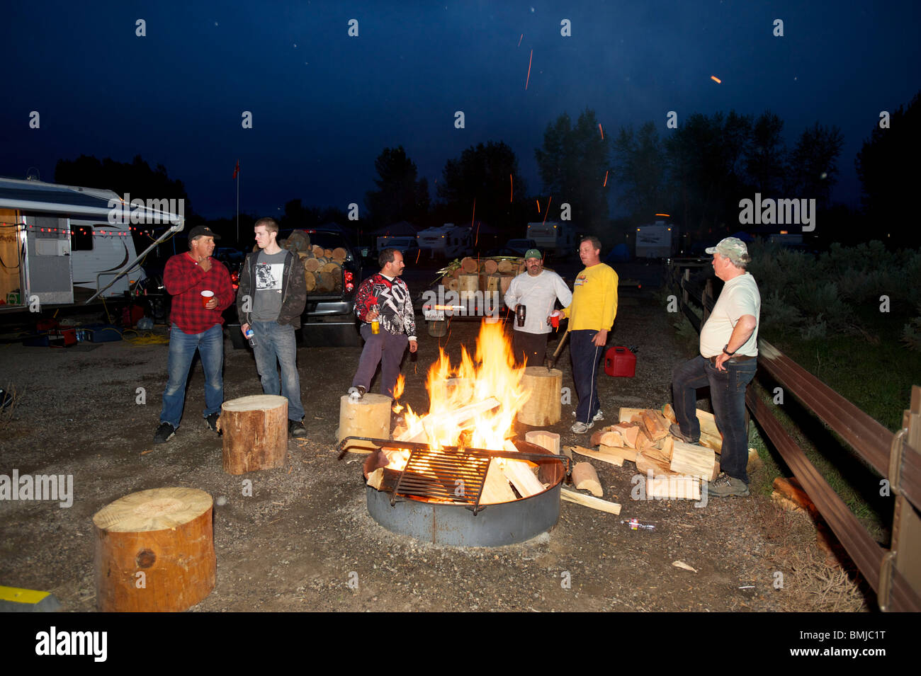 Group of friends around a campfire Stock Photo - Alamy