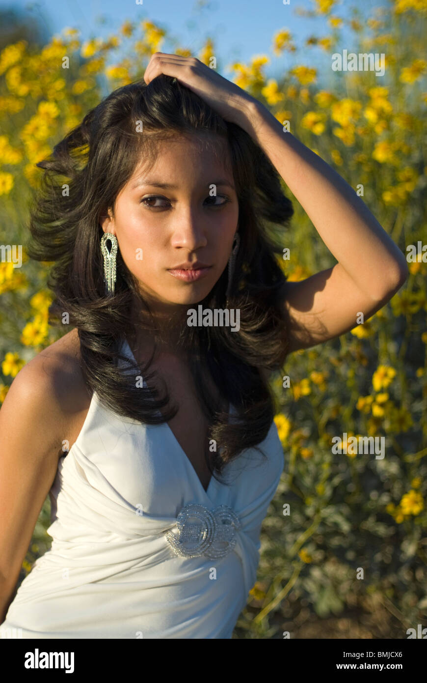 A young and very pretty multi-racial woman poses with her hand in her ...