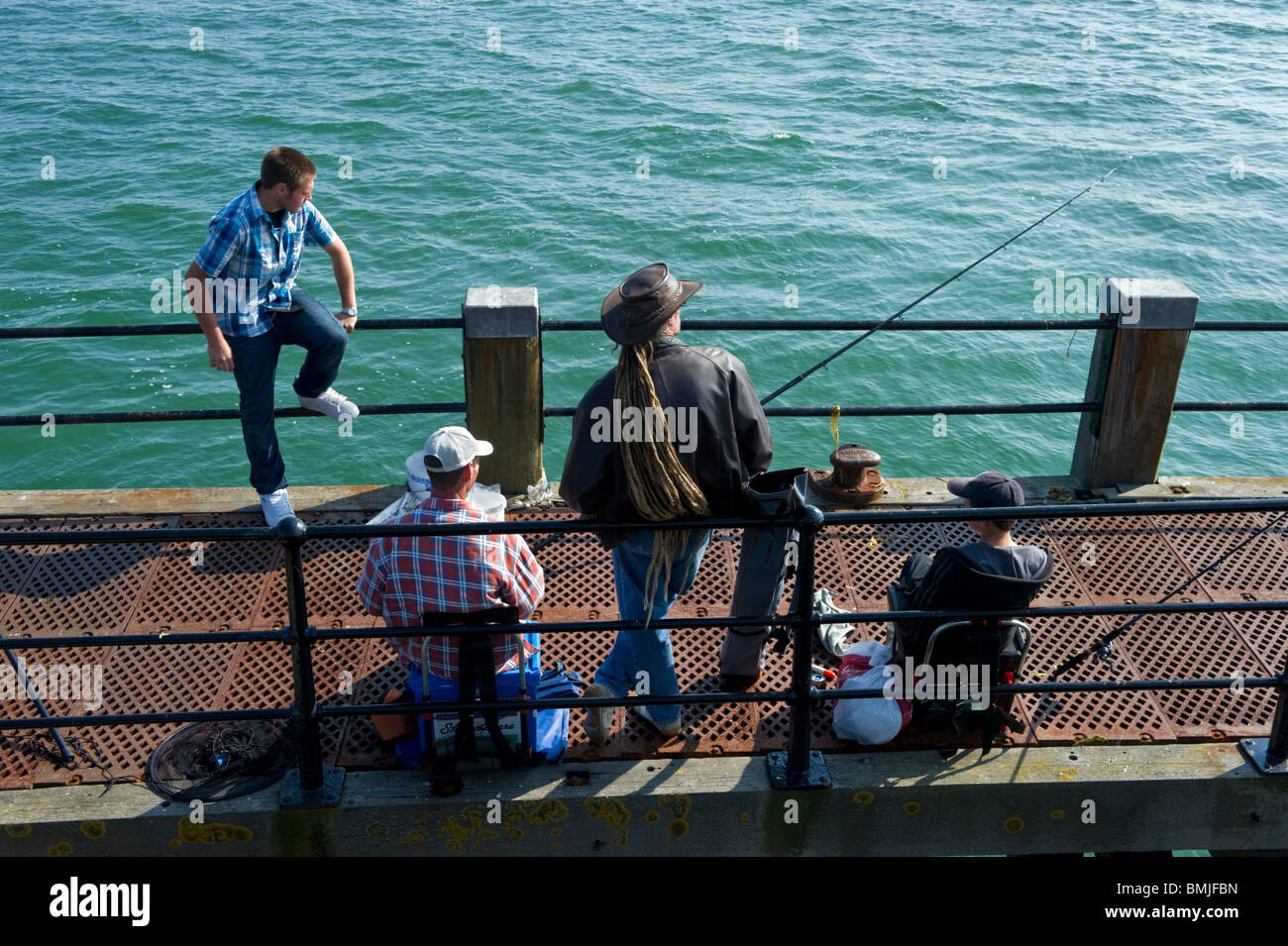 A group of young men fishing in the sea from the lower deck of Worthing ...