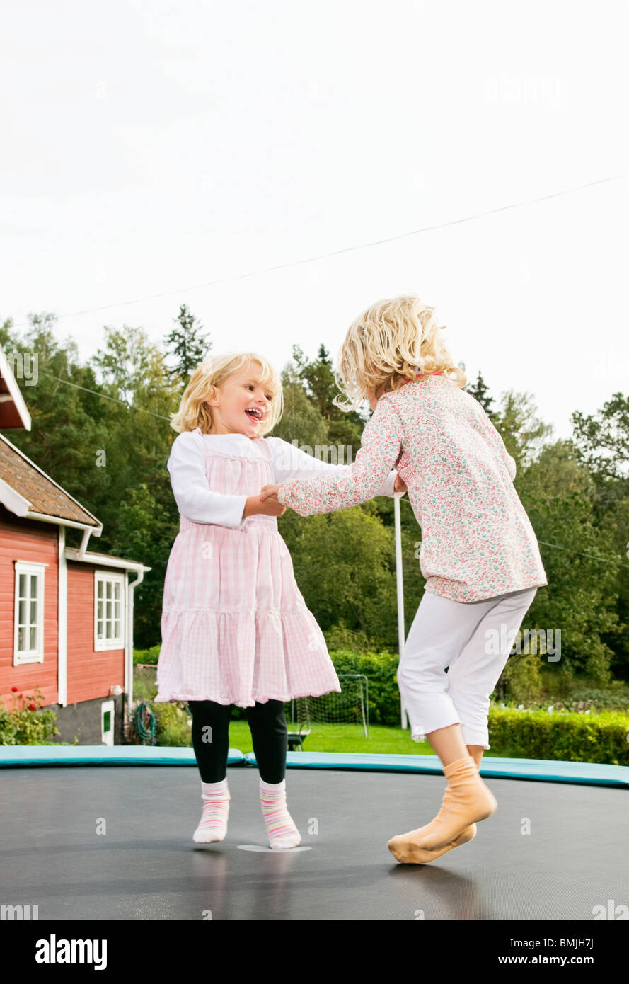 Two sisters jumping on rebouncer Stock Photo - Alamy