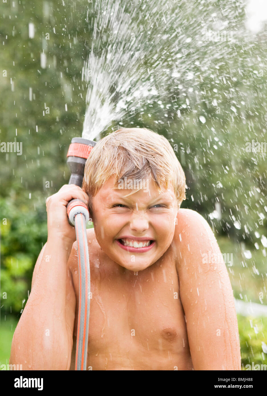 Boy holding water hose Stock Photo - Alamy