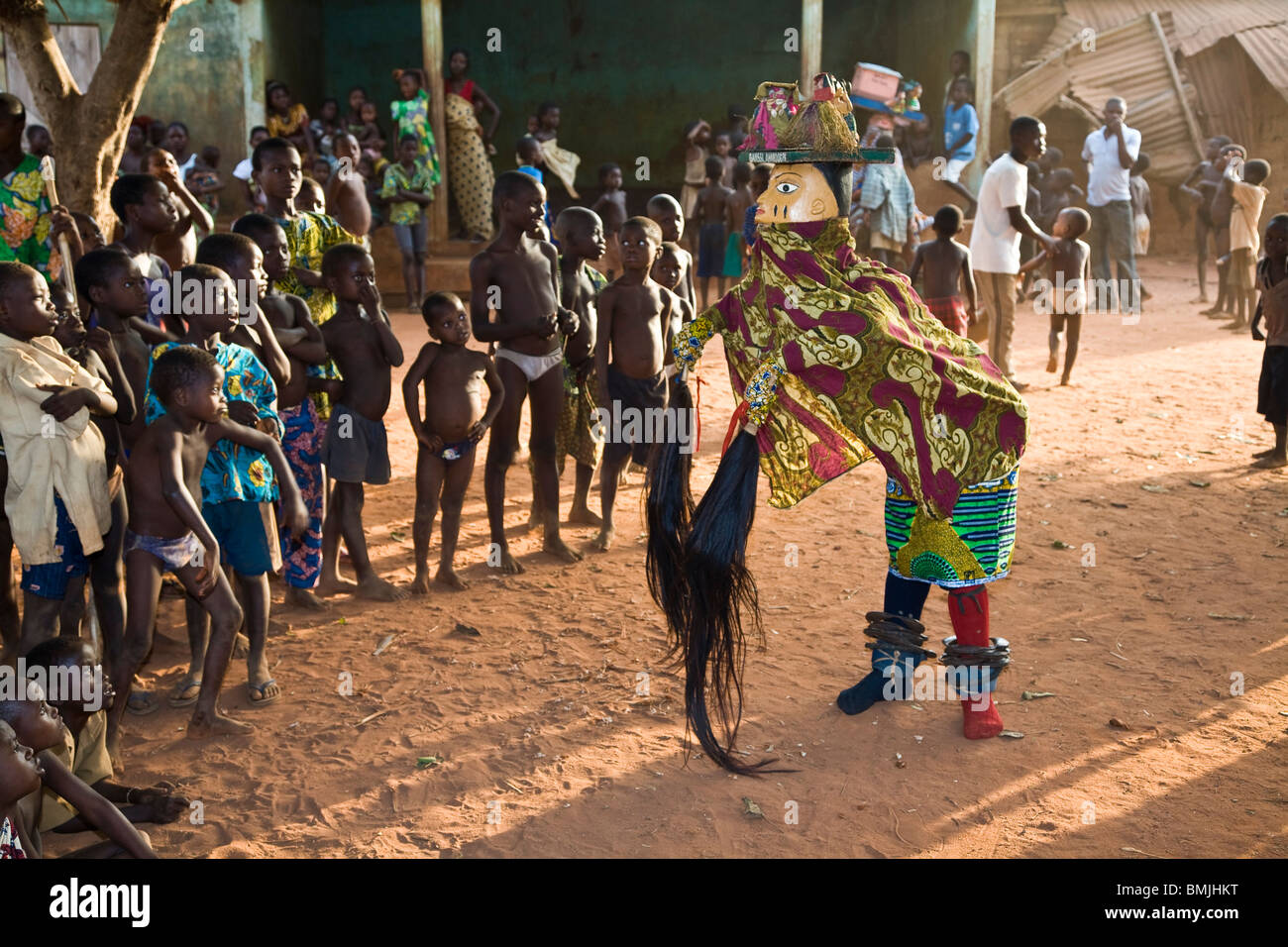 West Africa, Benin. Men and children watch Gelede Mask Dancers perform ...