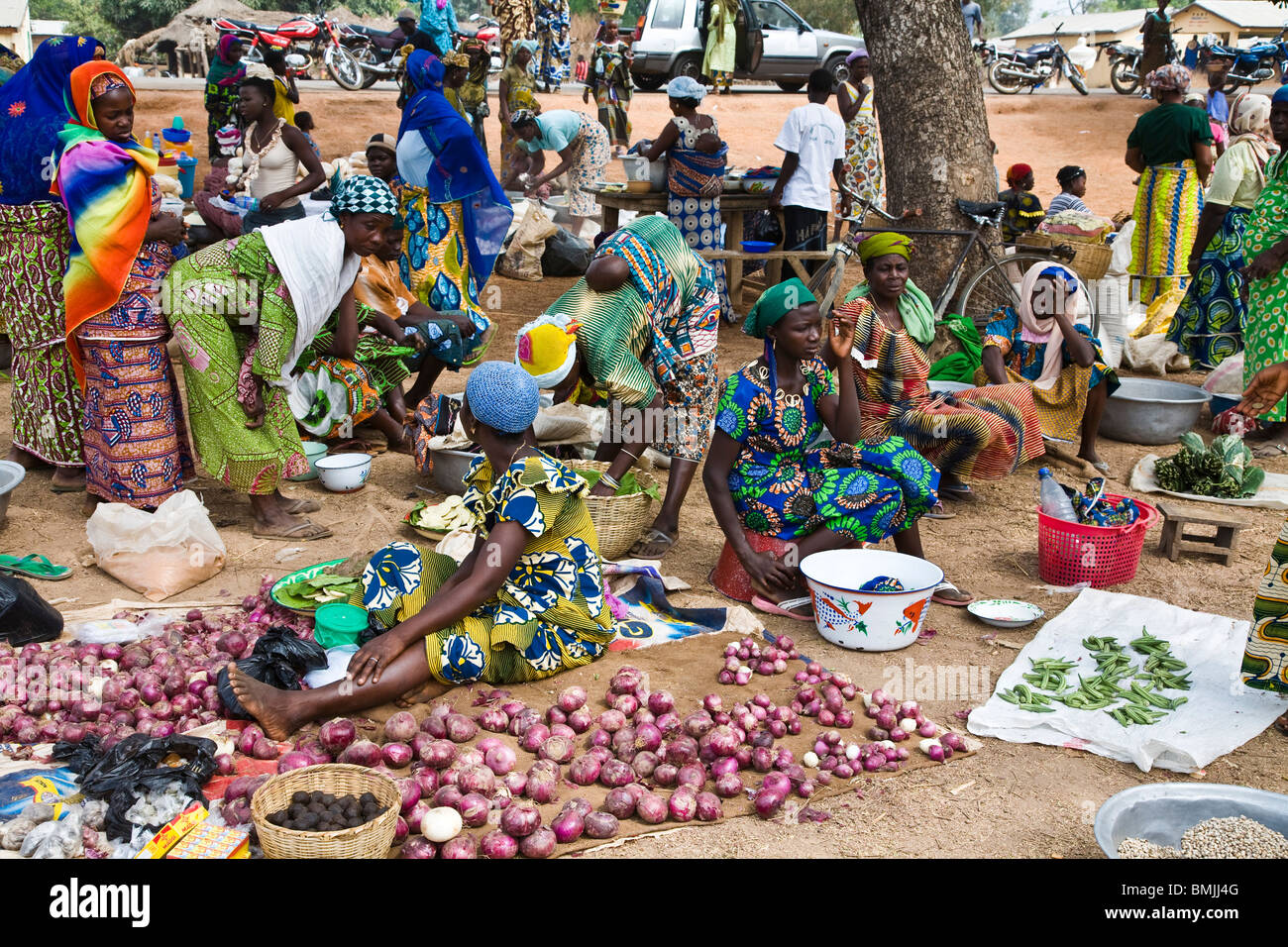 West Africa, Benin. Colorfully dressed women sit in open-air market ...