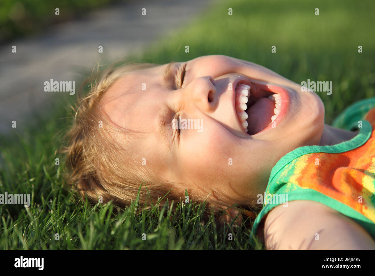 Happy cute girl laughing on a grass field Stock Photo - Alamy