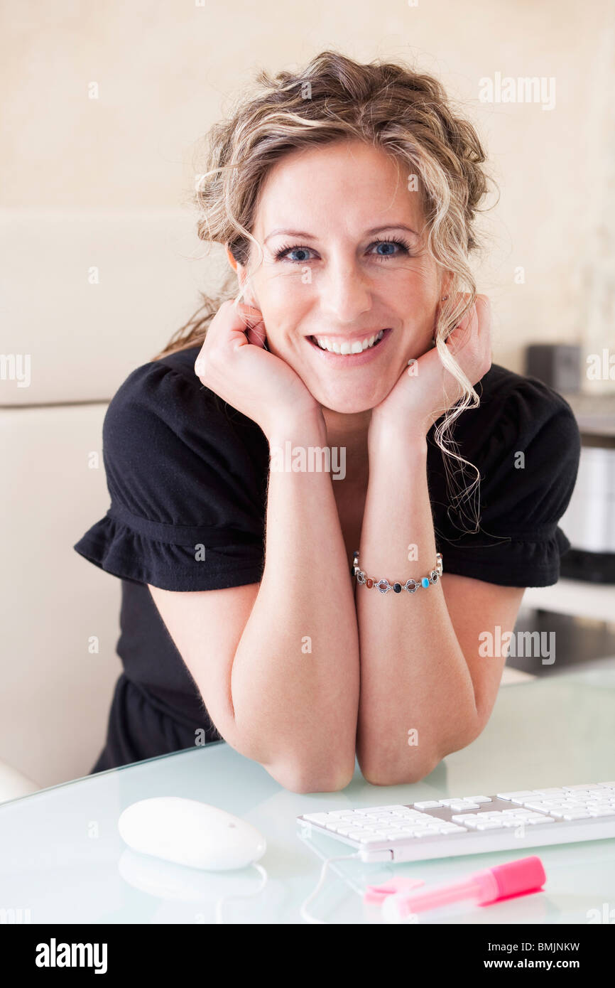 Woman sitting at her desk smiling Stock Photo - Alamy