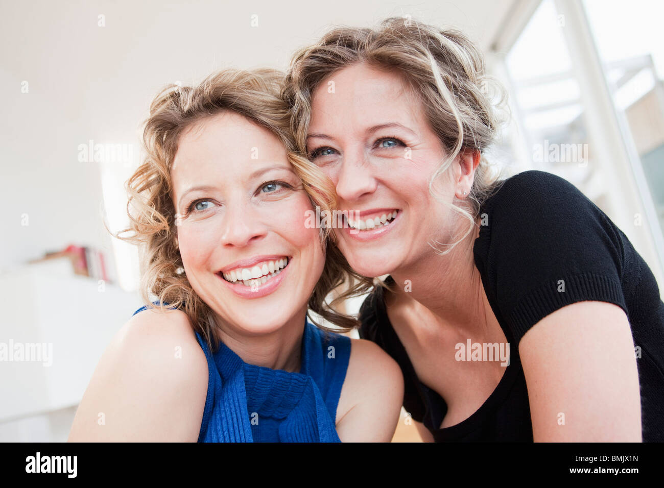 Two woman cheek to cheek smiling Stock Photo - Alamy