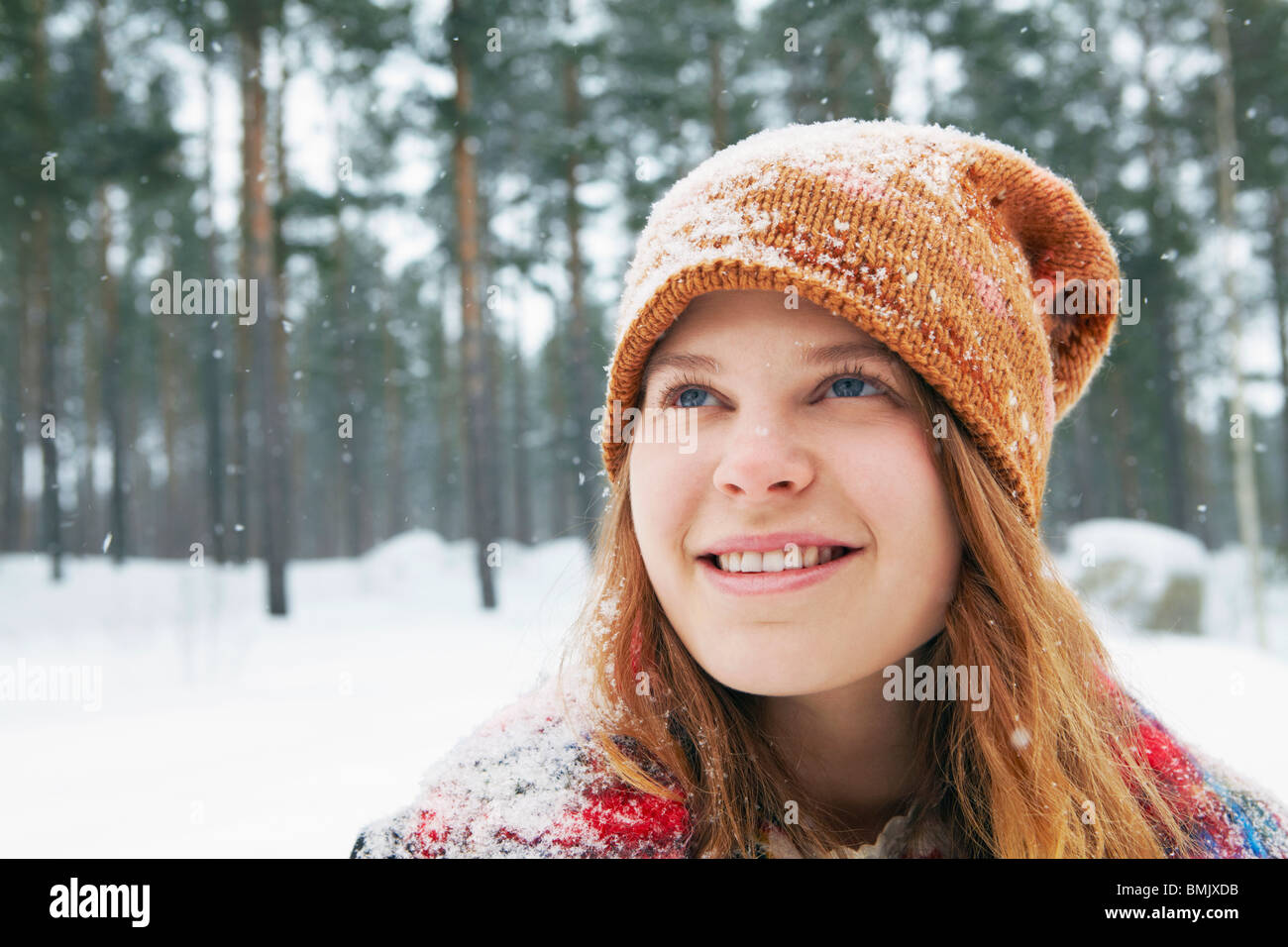 Smiling young woman watching snow fall Stock Photo - Alamy