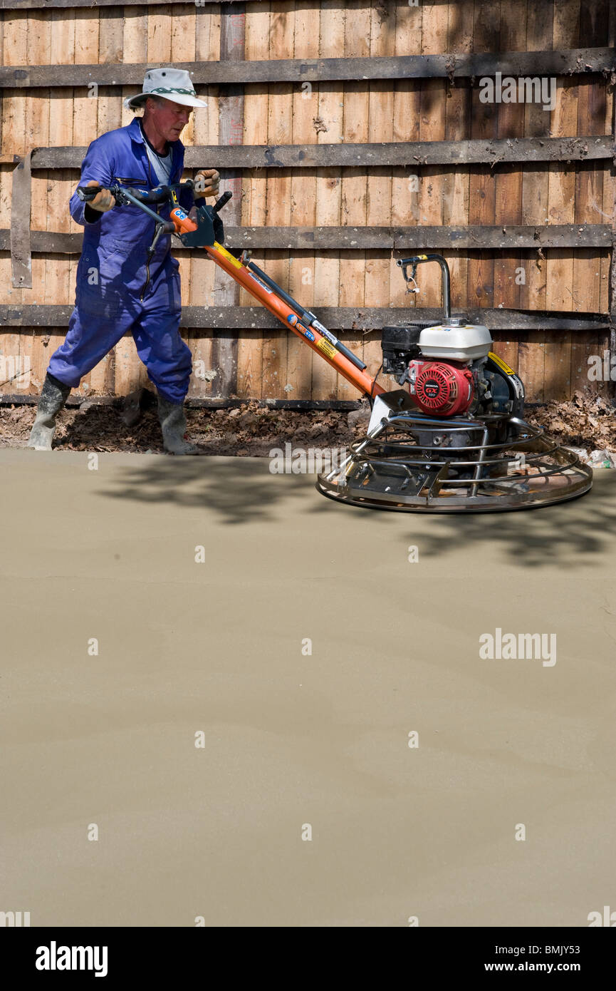 man levelling concrete base with power float Stock Photo - Alamy