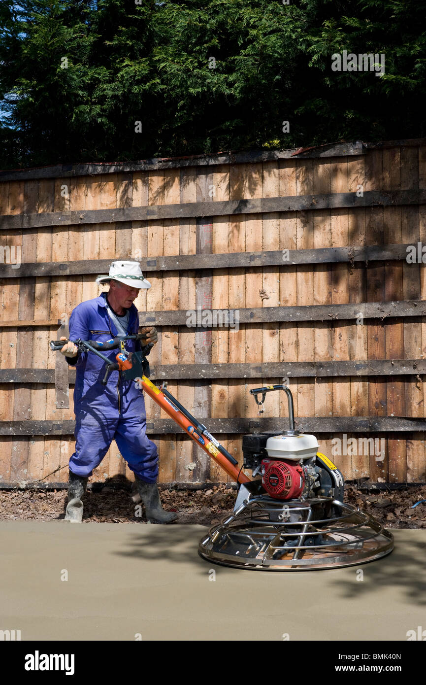man levelling concrete base with power float Stock Photo - Alamy