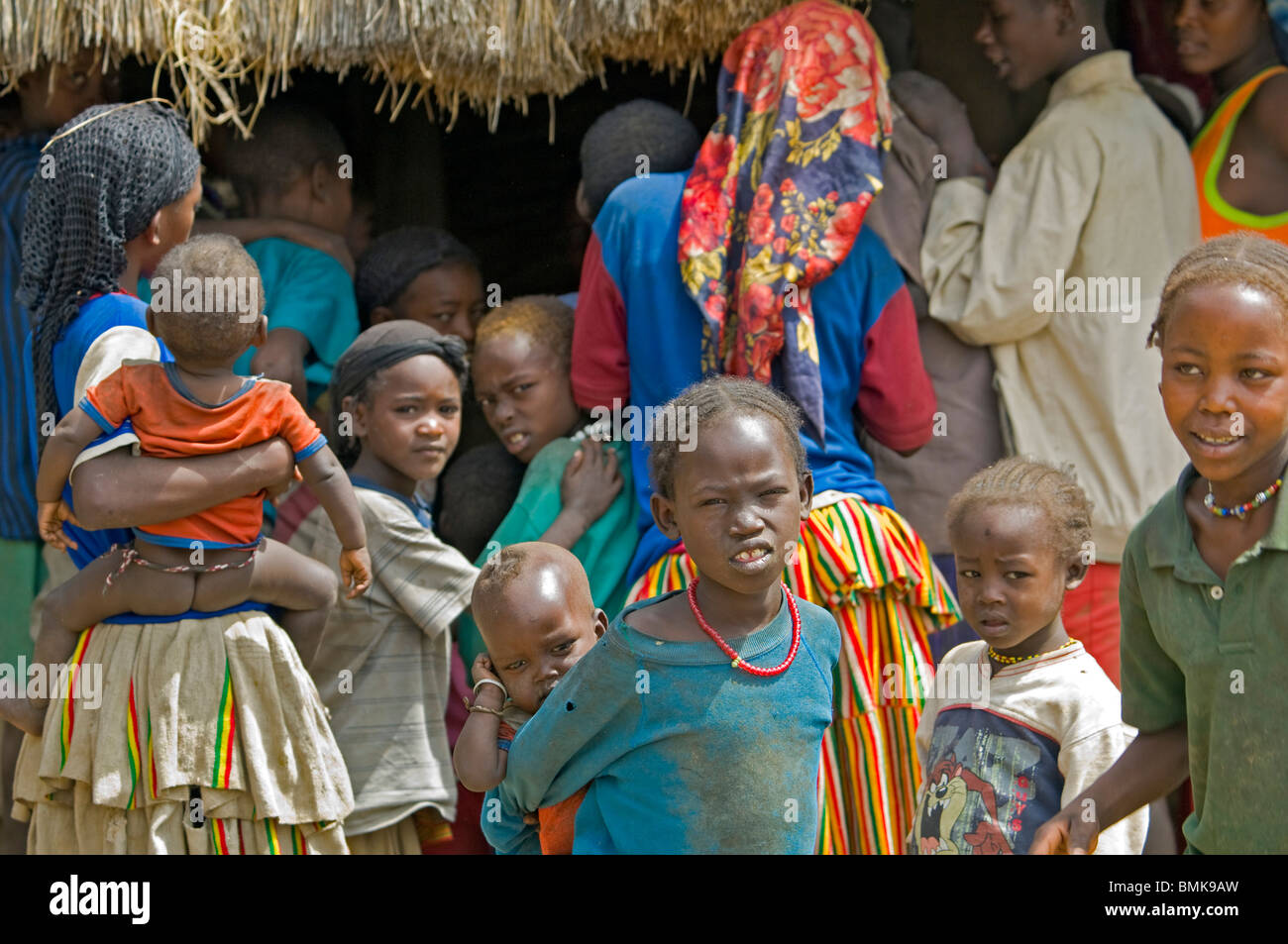 Colorfully dressed villagers of all ages crowd into the grassed-roofed ...