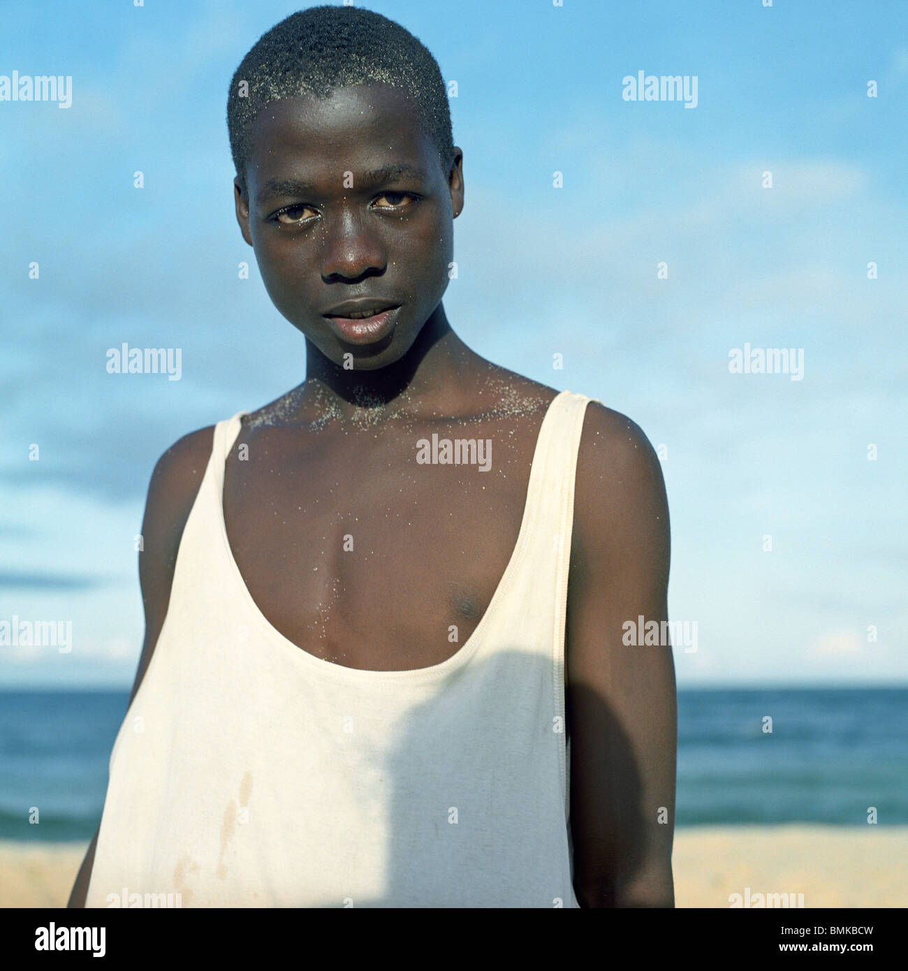 An african teenaged boy in Kenya standing on the beach with his back to ...
